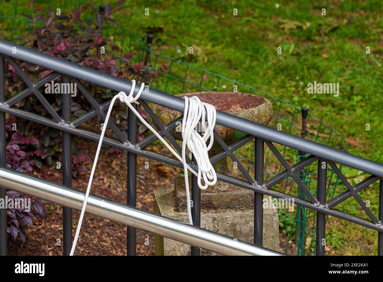 White rope wrapped around a black metal railing in a garden with ...