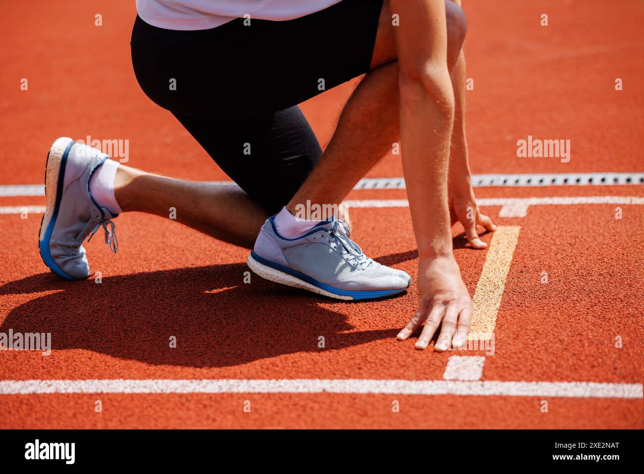 A determined athlete is in a crouched position at the starting line of ...