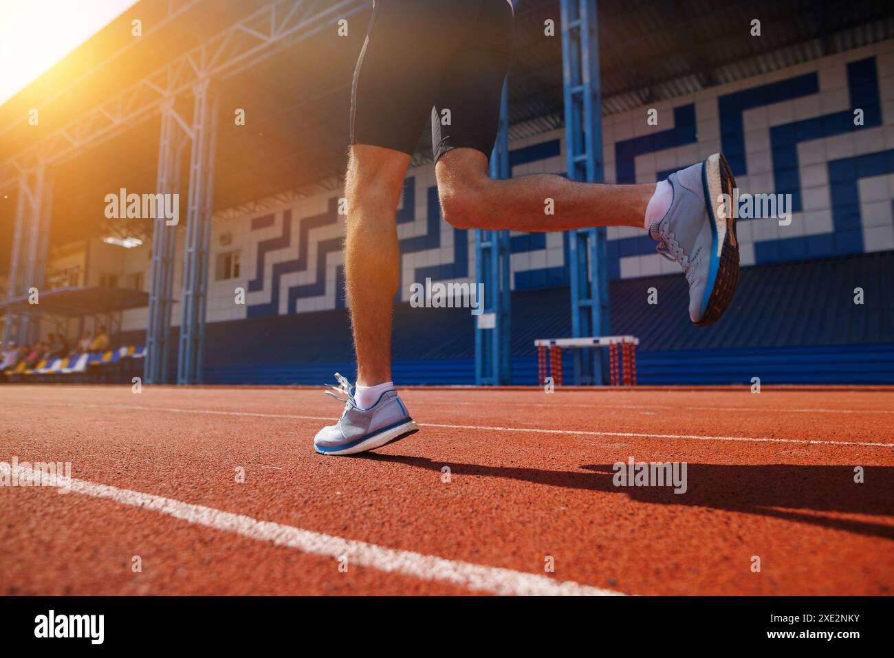 An athlete running on a track at a stadium, captured during sunrise ...