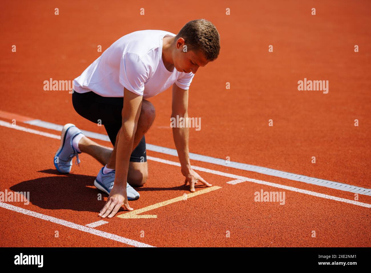 A determined athlete is in a crouched position at the starting line of ...