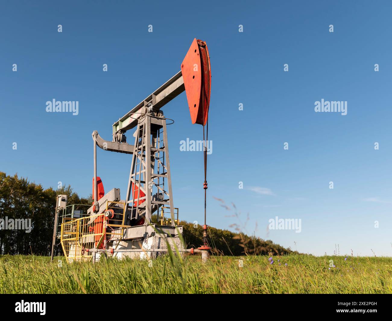 Operating oil and gas well in oil field, profiled against the blue sky ...