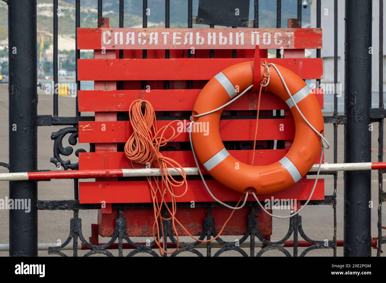 Orange lifebuoy with ropes hanging on a shield with a gaff. Inscription ...