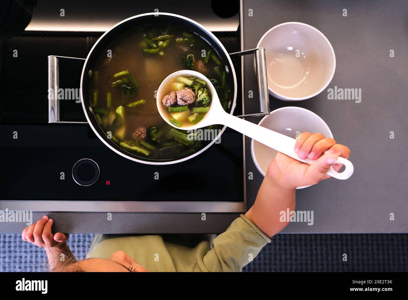 The girl serves the soup with a ladle Stock Photo - Alamy