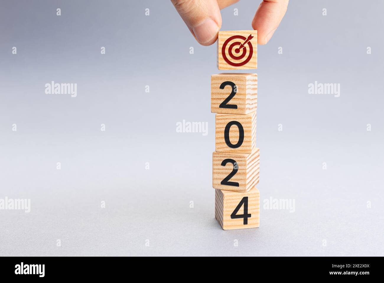 Hand holding a target icon on top of Wooden blocks with 2024 number ...