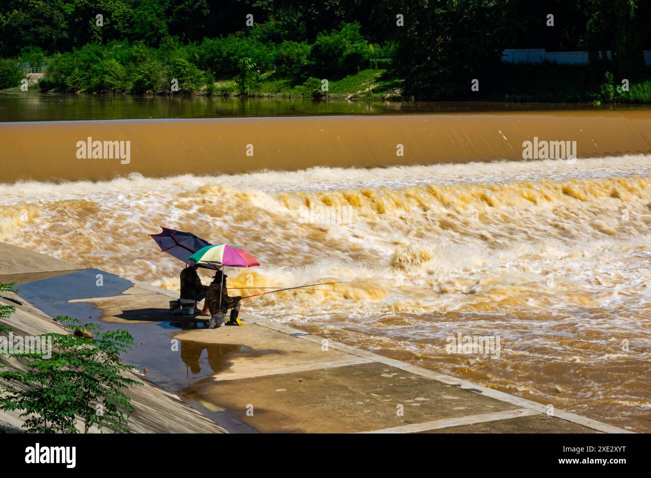Silhouette of two men sitting under colorful umbrellas fishing in the ...