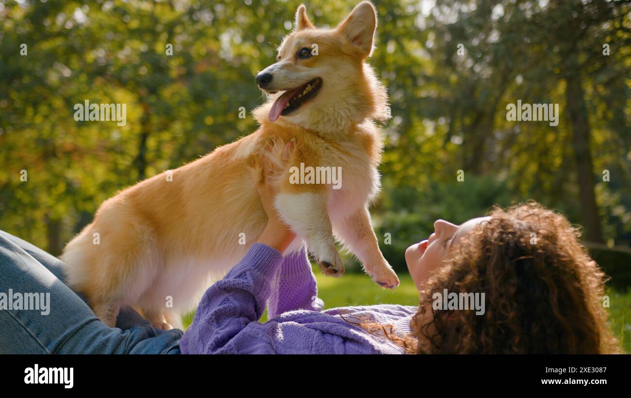 Purebred dog corgi playing with girl embracing outdoors pets friendly ...