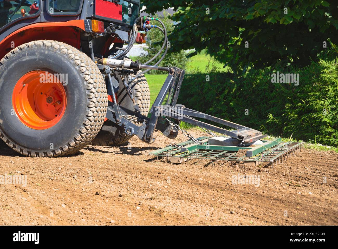 Small tractor with harrow loosens soil - garden design Stock Photo - Alamy