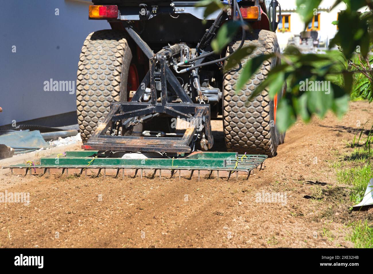 Soil cultivation in the garden with tine harrow and small tractor ...