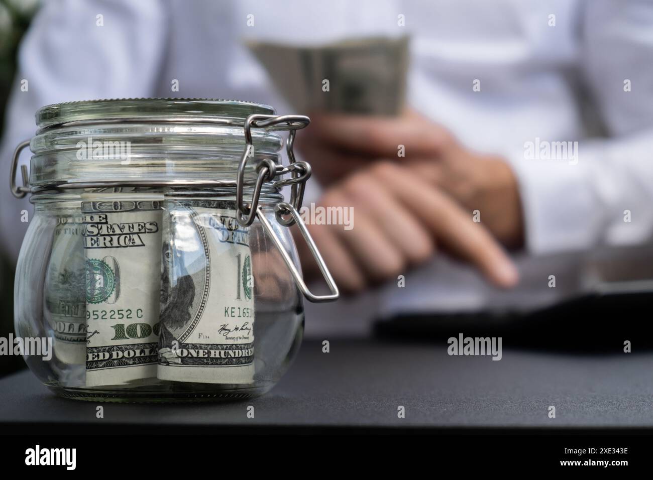 Dollar Banknote Saving Money In Glass Jar. Unrecognizable man calculate ...