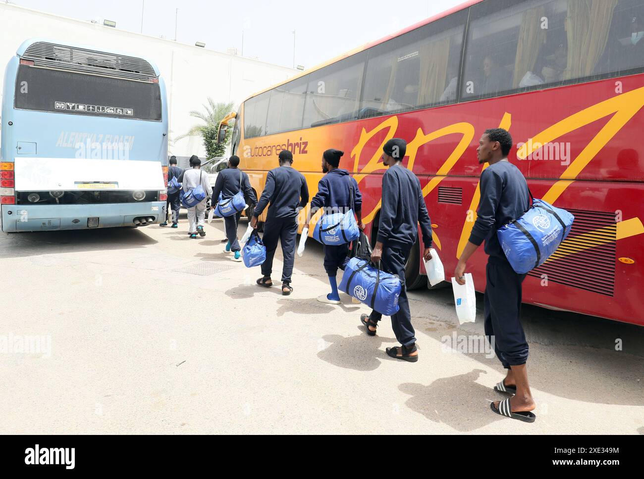 Tripoli, Libya. 25th June, 2024. Migrants line up to get on a bus ...