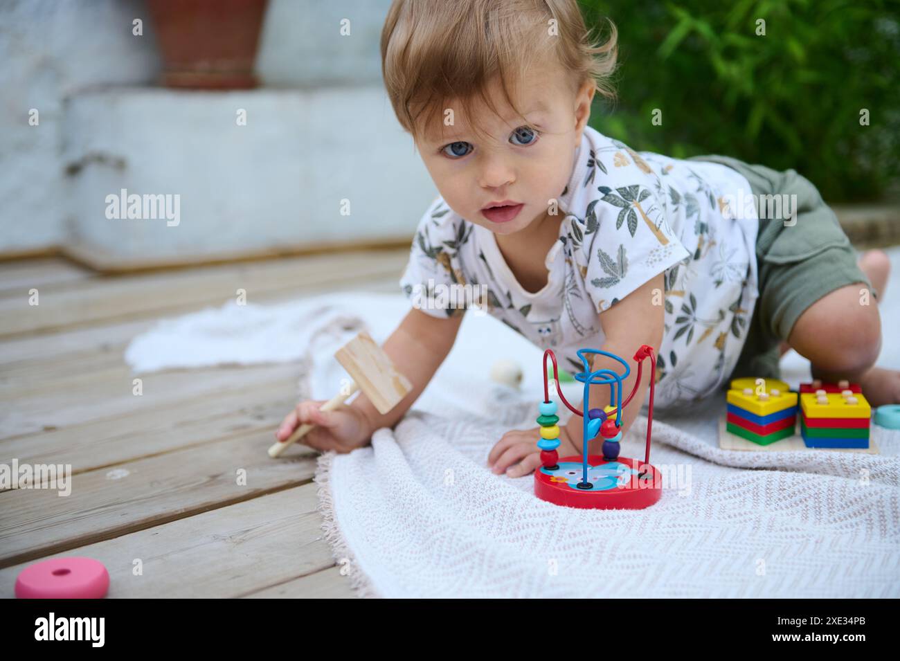 A cute baby crawling on a wooden floor while playing with colorful ...