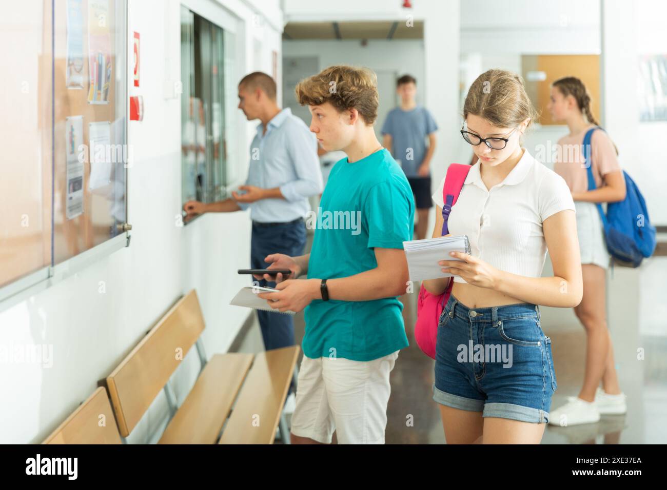 Teenage boy and girl students checking classes schedule Stock Photo - Alamy