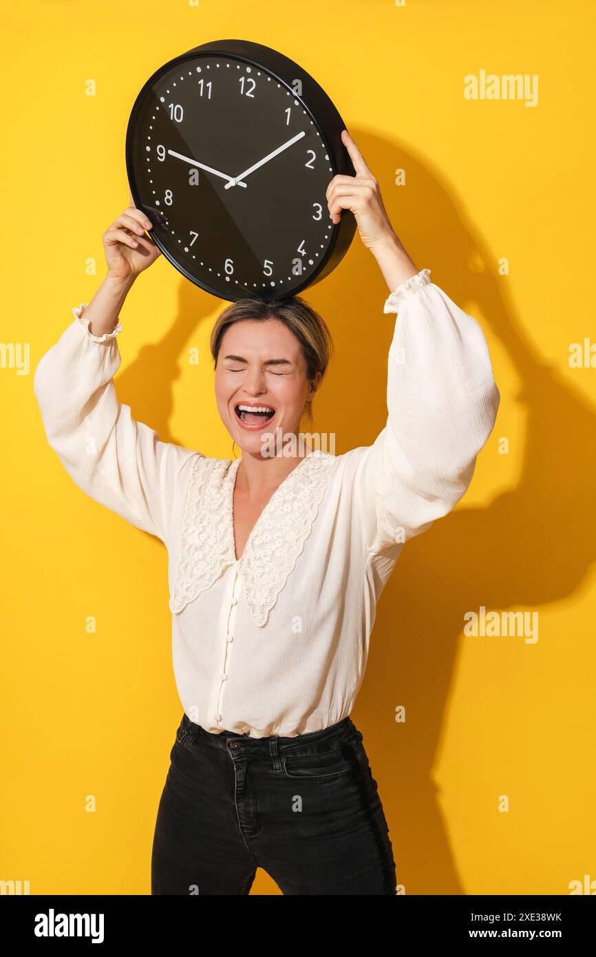 Shouting cheerful woman holding big clock on yellow background Stock ...