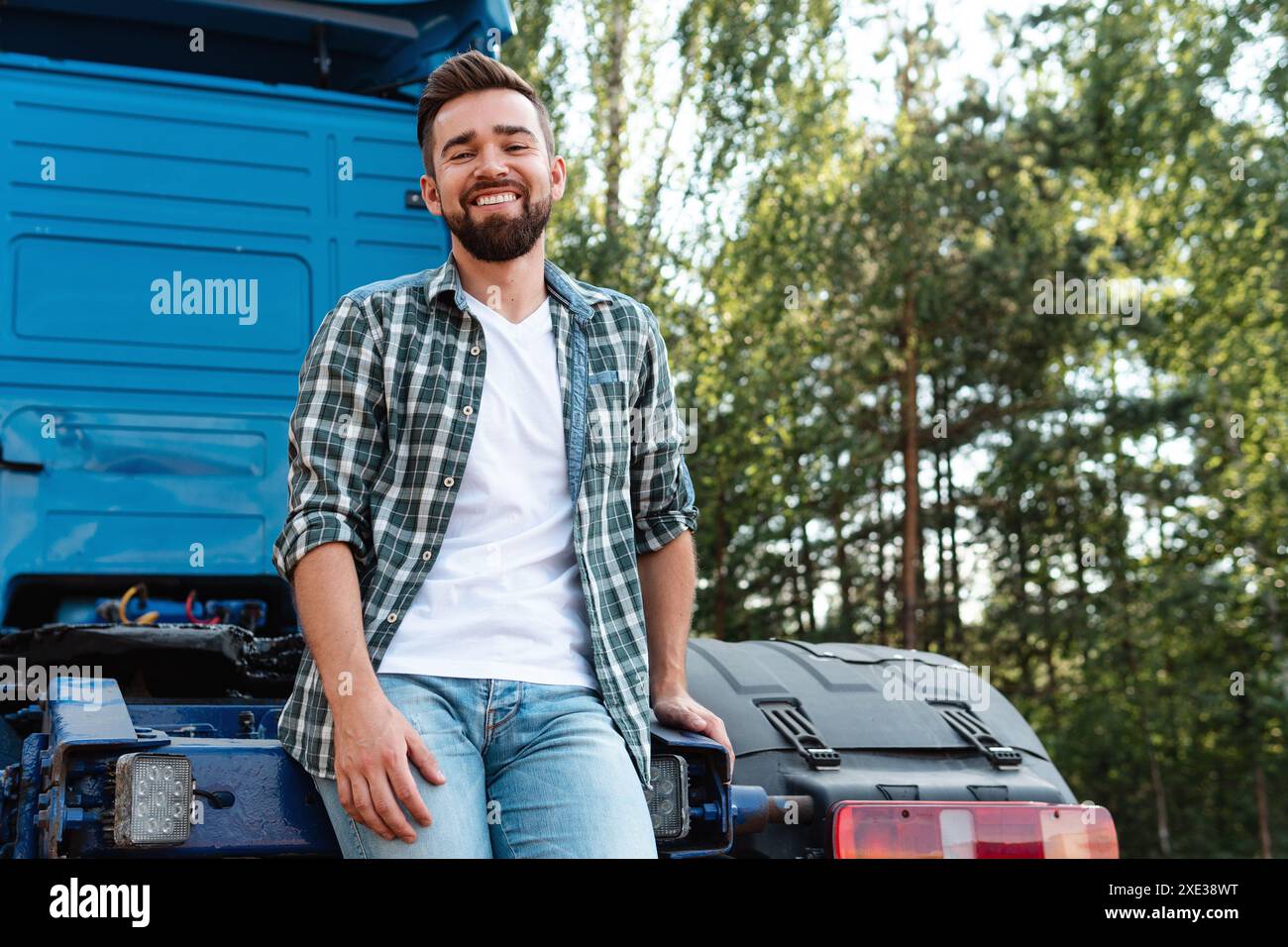 Young smiling male truck driver beside his blue cargo truck Stock Photo ...