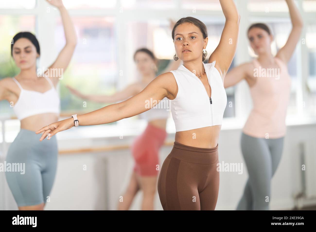 Diligent beautiful young female dancer exercising ballet moves during ...