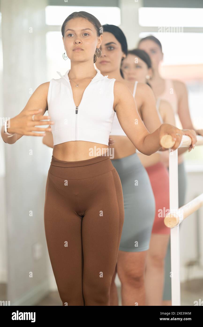 Young girl practicing first arm position holding by ballet barre Stock ...