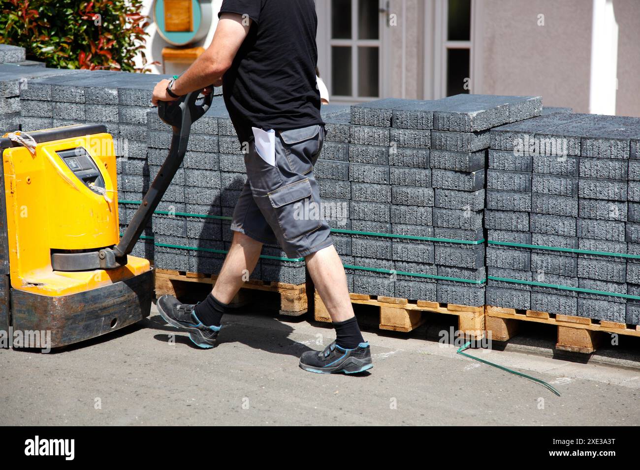 A fork pallet truck stacker with stack of concrete paving slabs ...