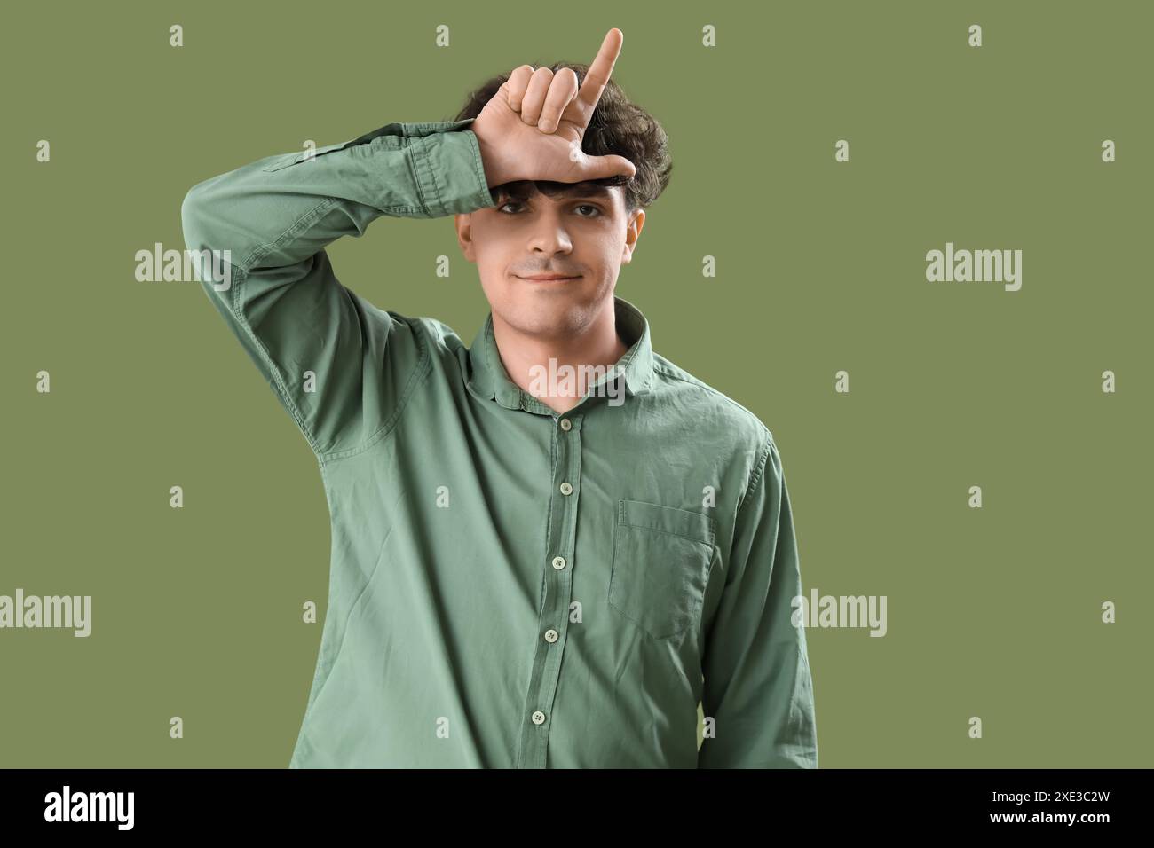 Young man showing loser gesture on green background Stock Photo - Alamy