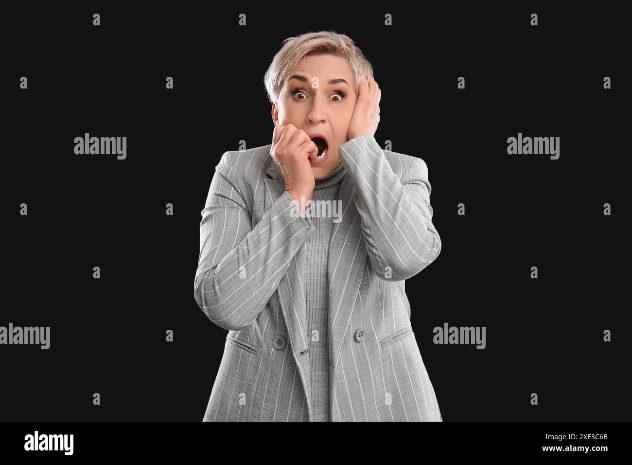 Scared mature woman on black background Stock Photo - Alamy
