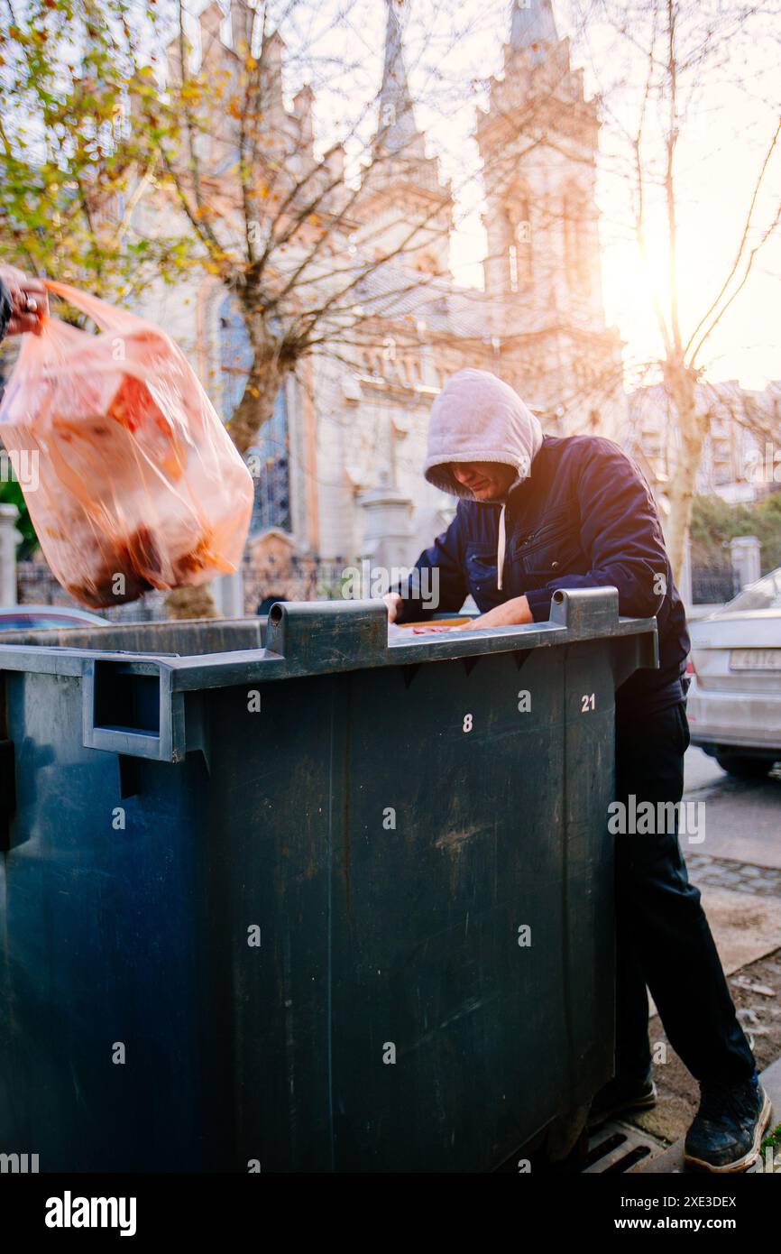 Homeless man looking into trash box in search for food on church ...