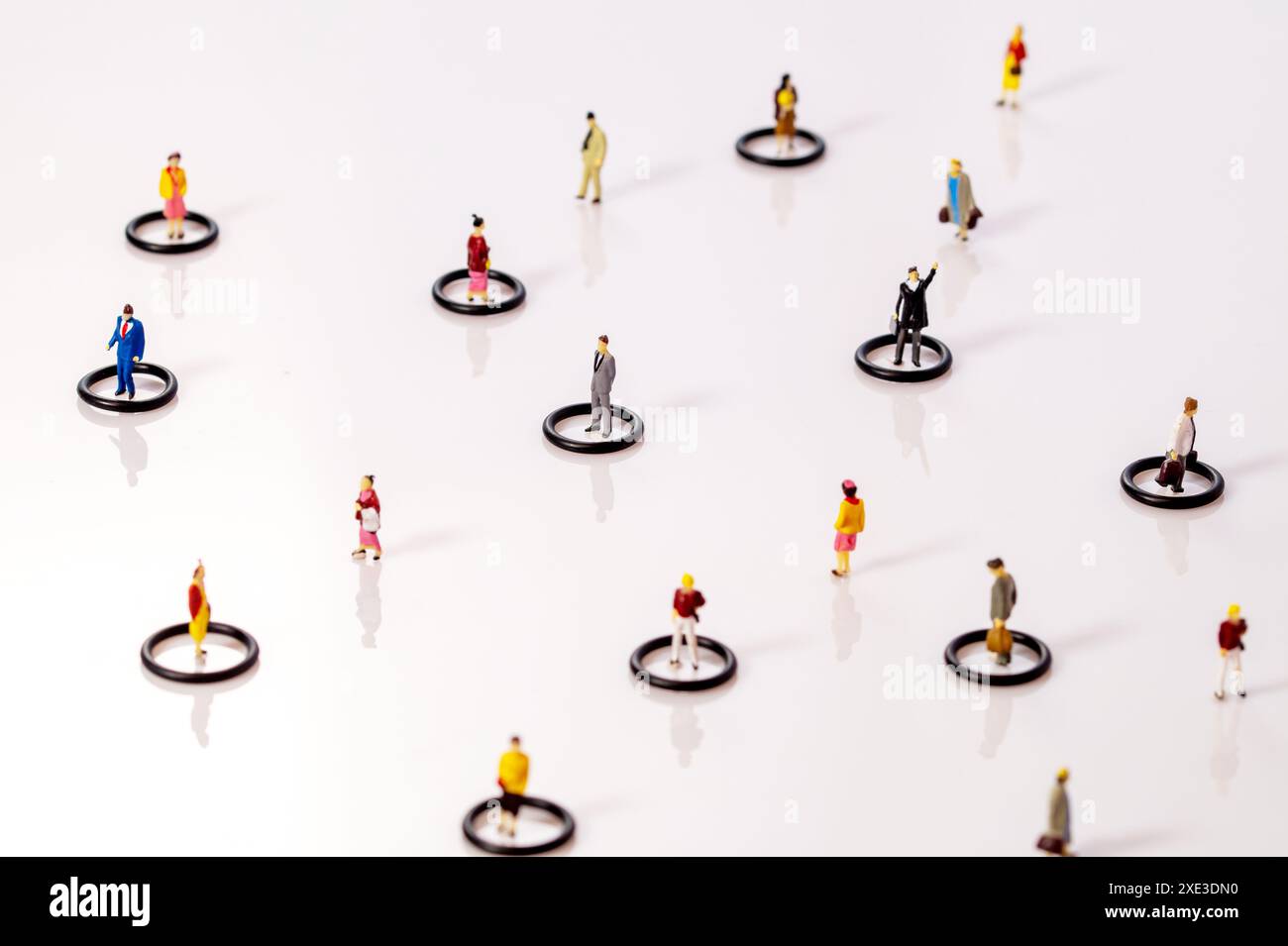 A circle of miniature toy people in circles keeping distance in public ...