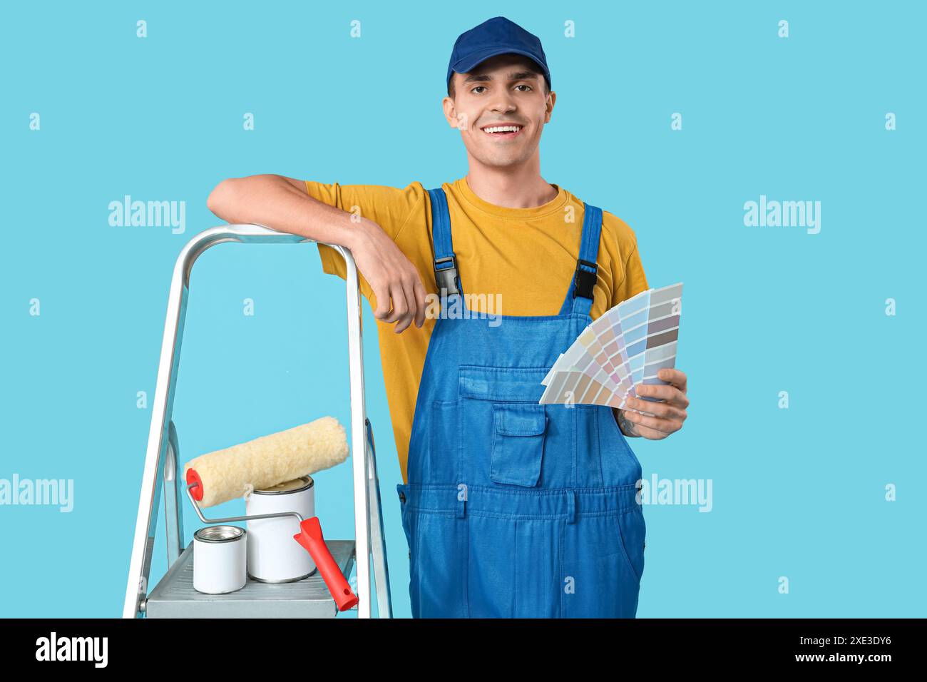 Young painter with color palettes and ladder on blue background Stock ...