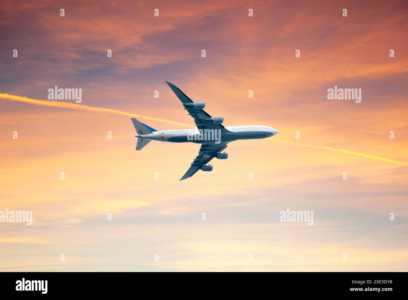 Airplane in the Sunset sky with condensation trail. Dramatic blue and ...