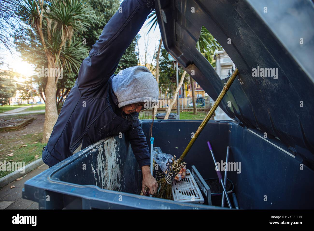 Homeless man looking into trash box in search for food on church ...