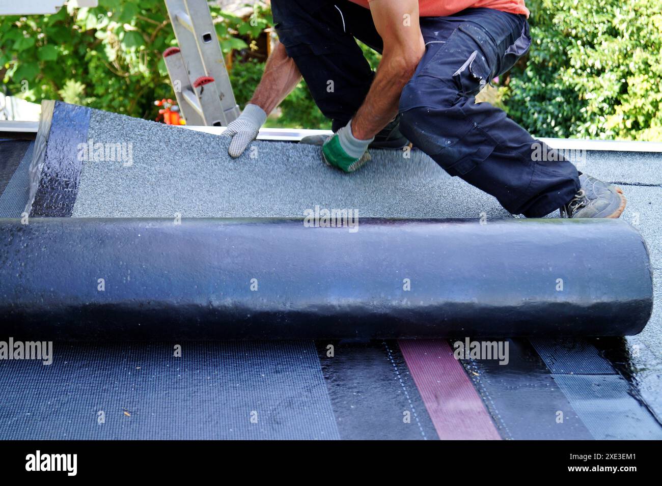 Worker installing tar foil on the rooftop of building. Flat roof ...