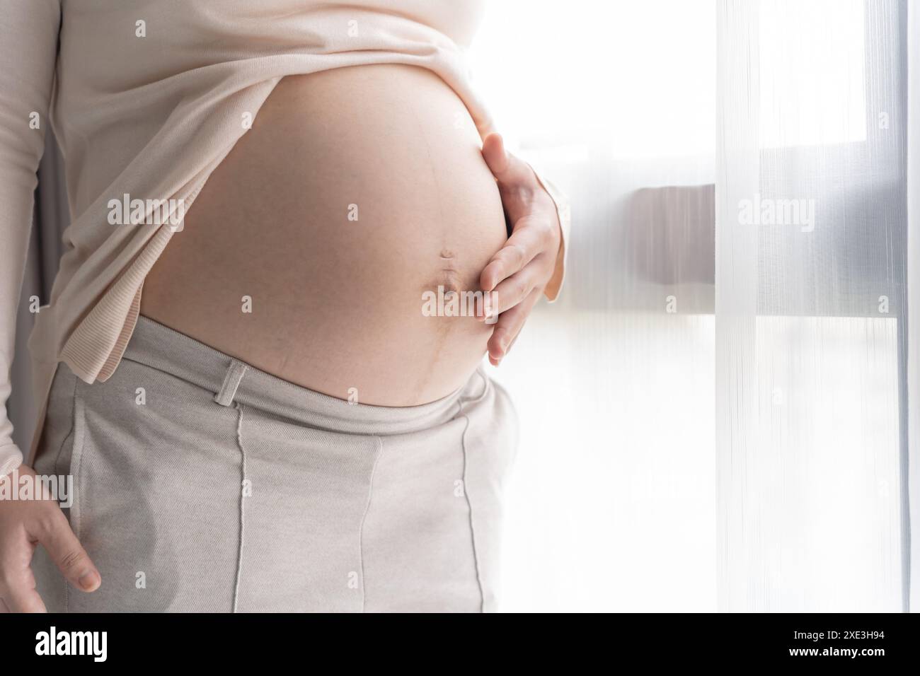 Pregnant woman holds hands on belly touching her baby caring about her ...