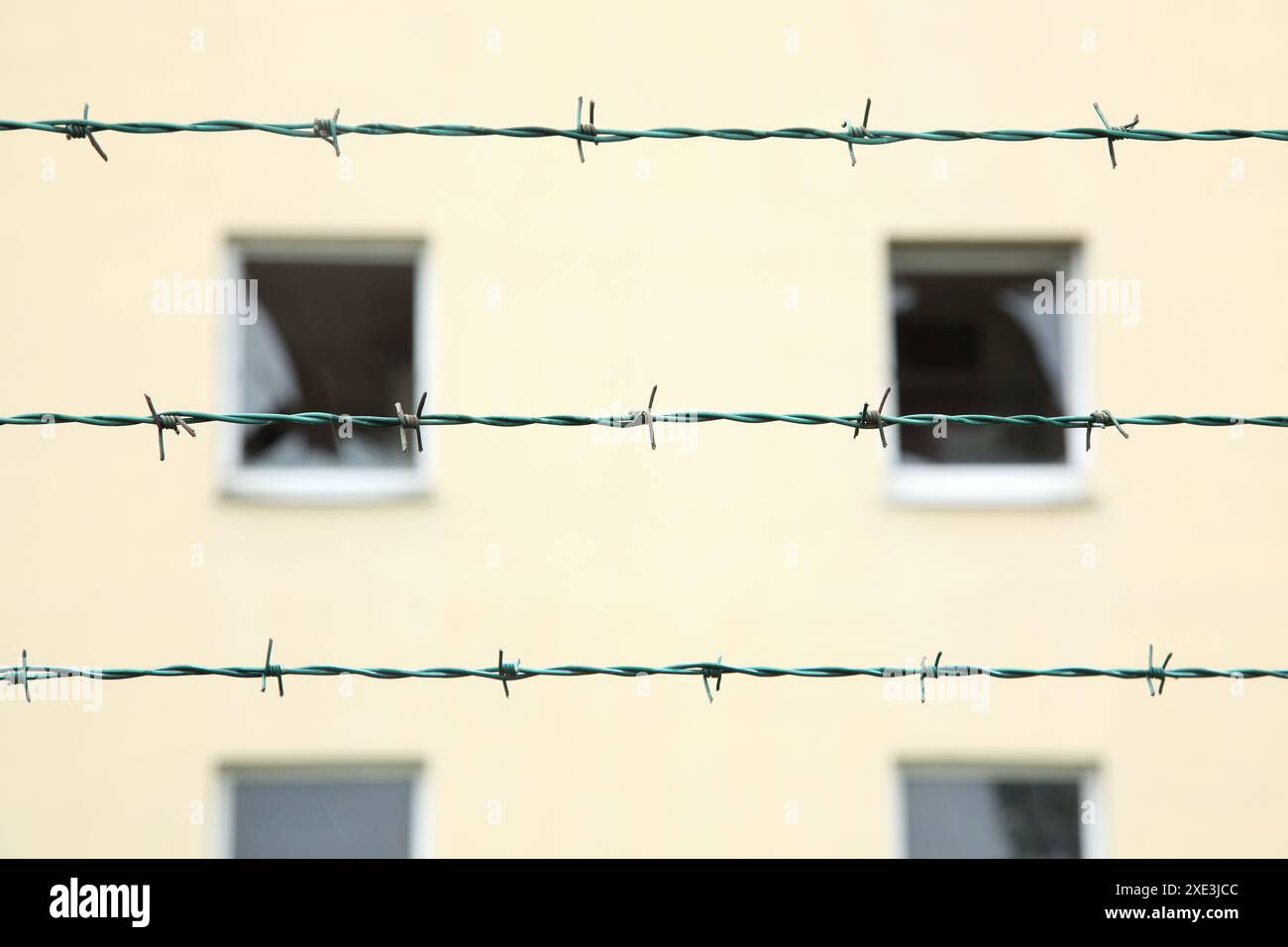 Rows of barbed wire against a abandoned residential building with ...