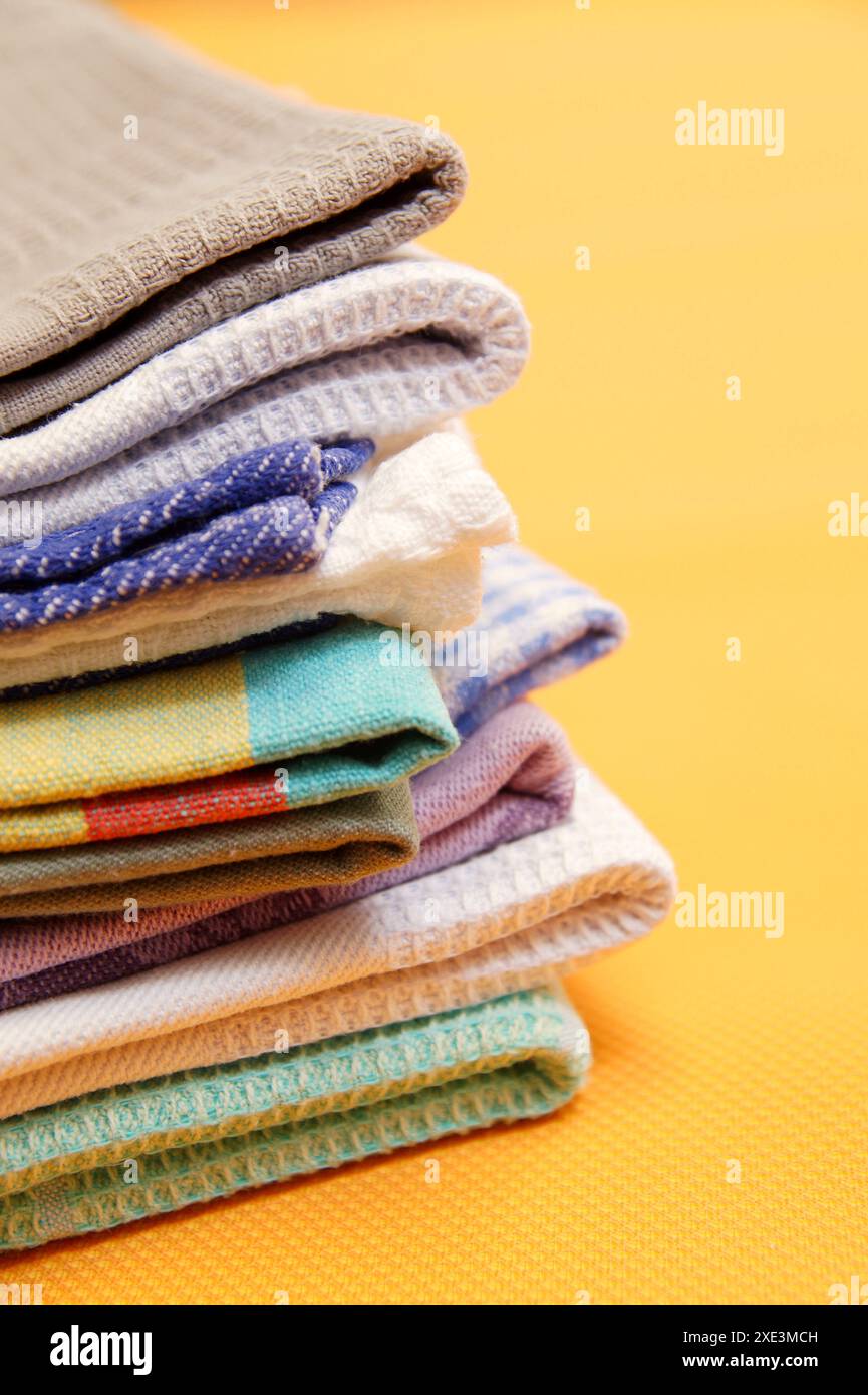 Pile of linen and cotton kitchen towels on a yellow background. Stack ...