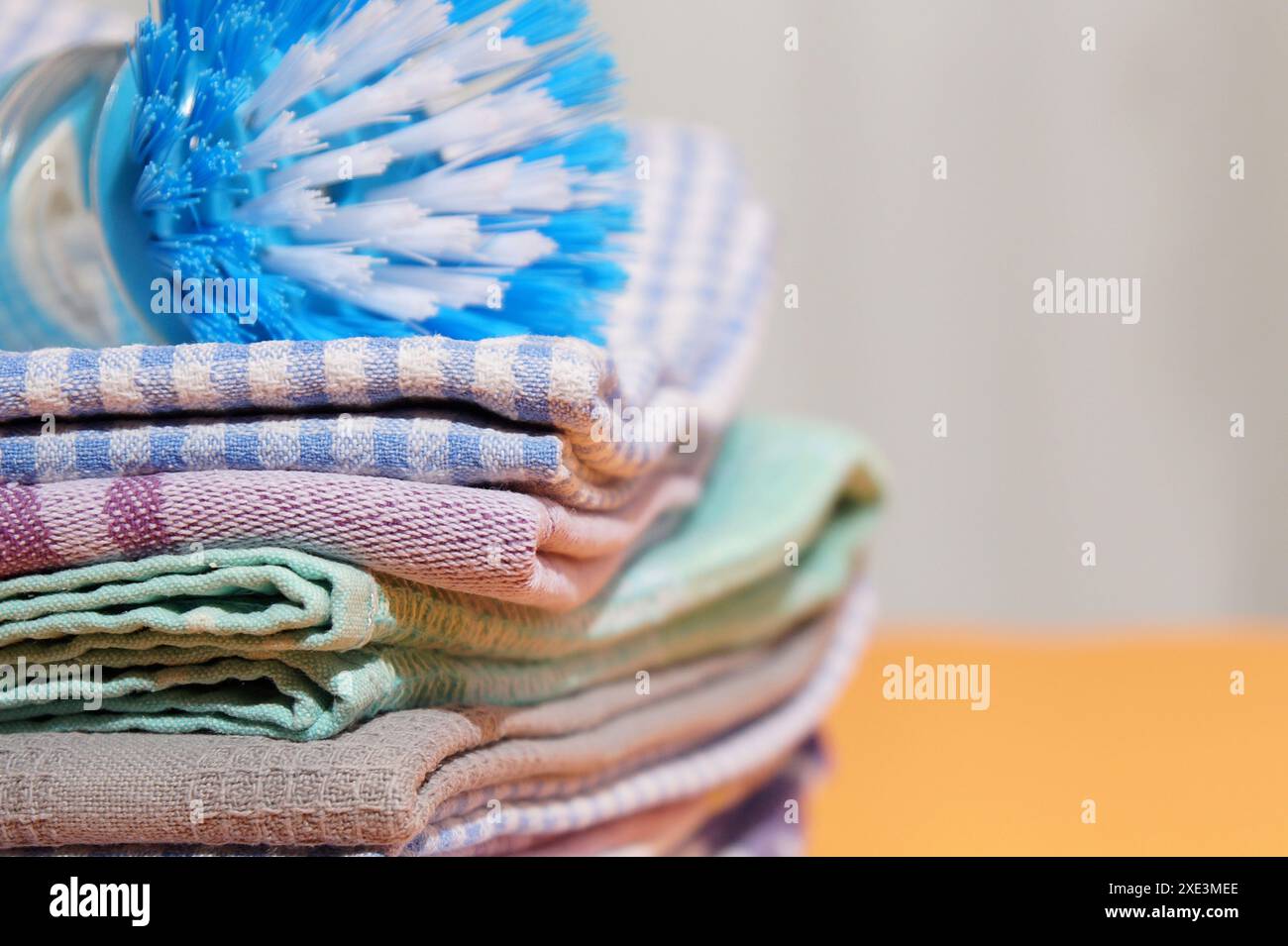 Pile of linen and cotton kitchen towels on yellow background, brush on ...
