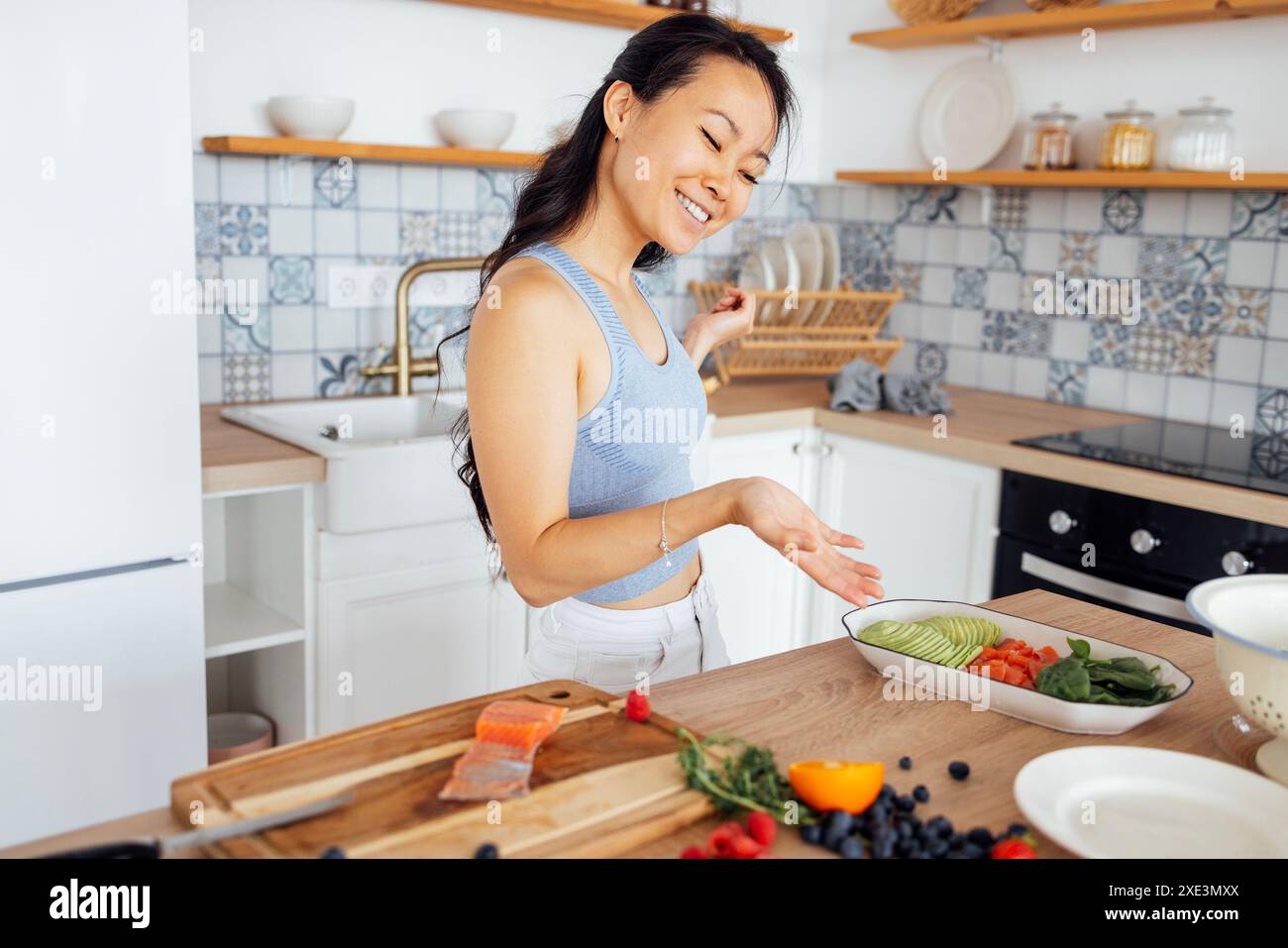 An attractive cute Asian woman smiles and cooks breakfast in the ...