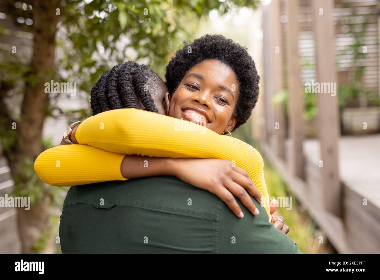 Hugging outdoors, African American couple with woman smiling warmly ...