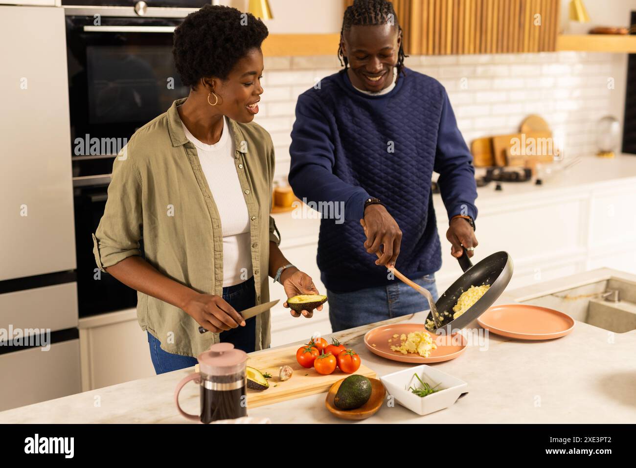 At home, Couple cooking breakfast together in modern kitchen, smiling ...