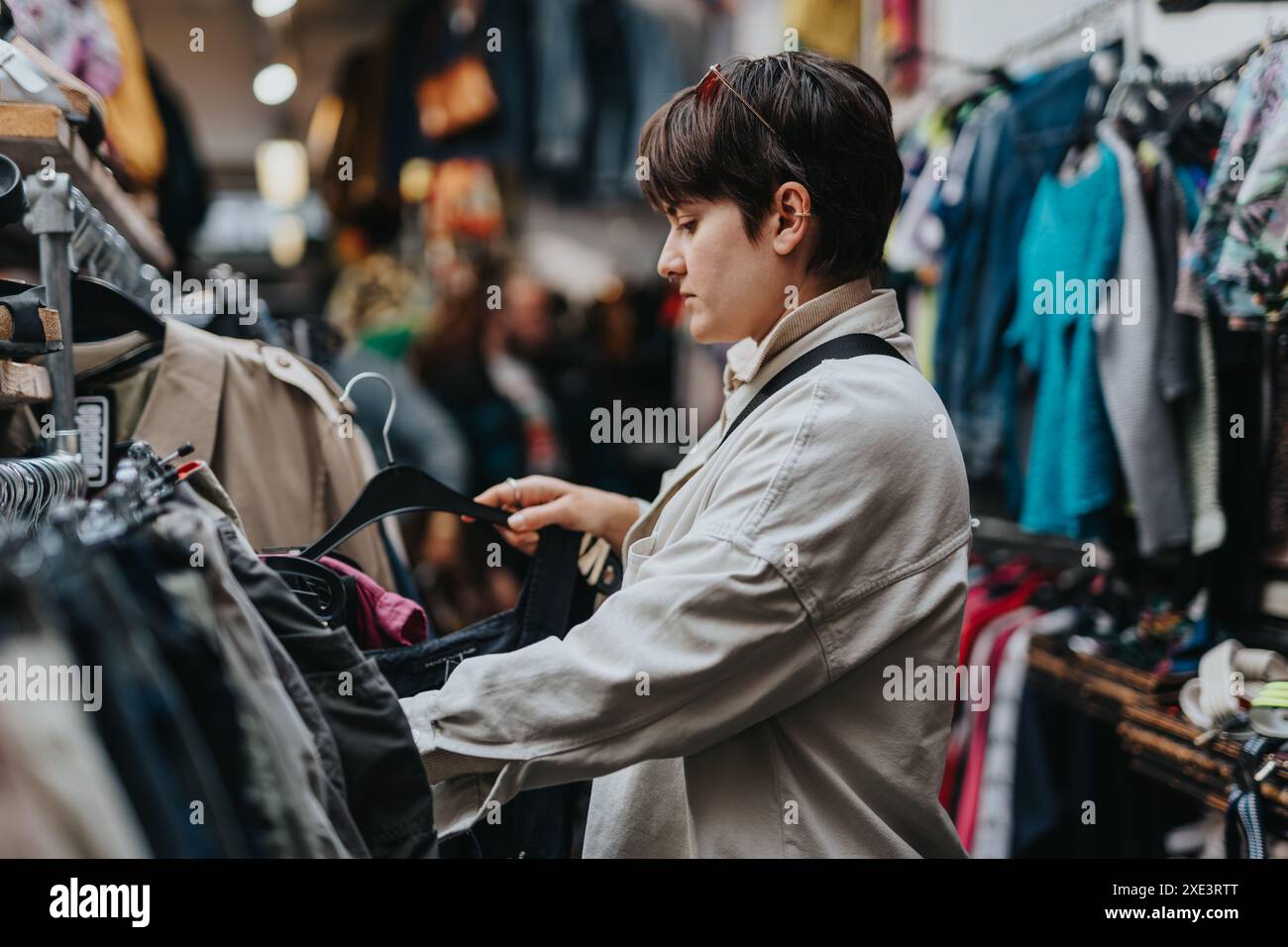 Person shopping in a thrift store, browsing through clothing racks in a ...