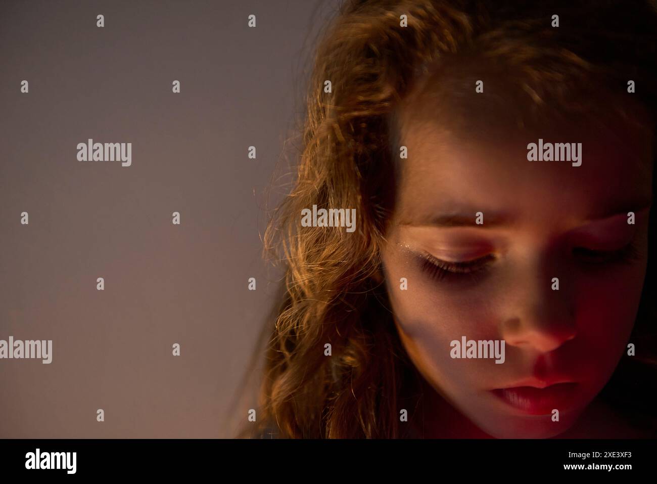 Girl with long brown hair and pulpy pink lips, looking down, thinking ...