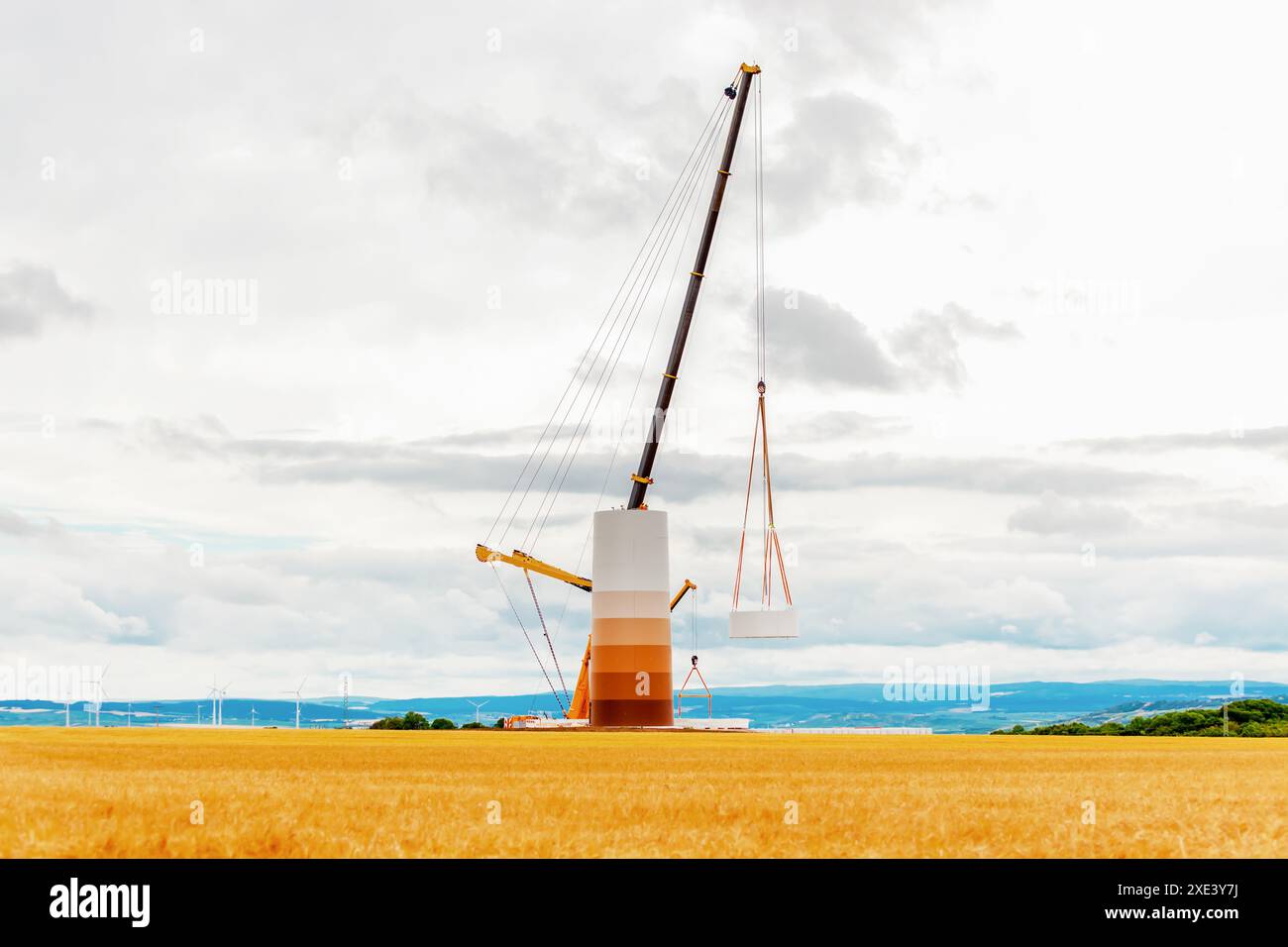 Building and assembling a construction windmill by crane. Farmland with ...