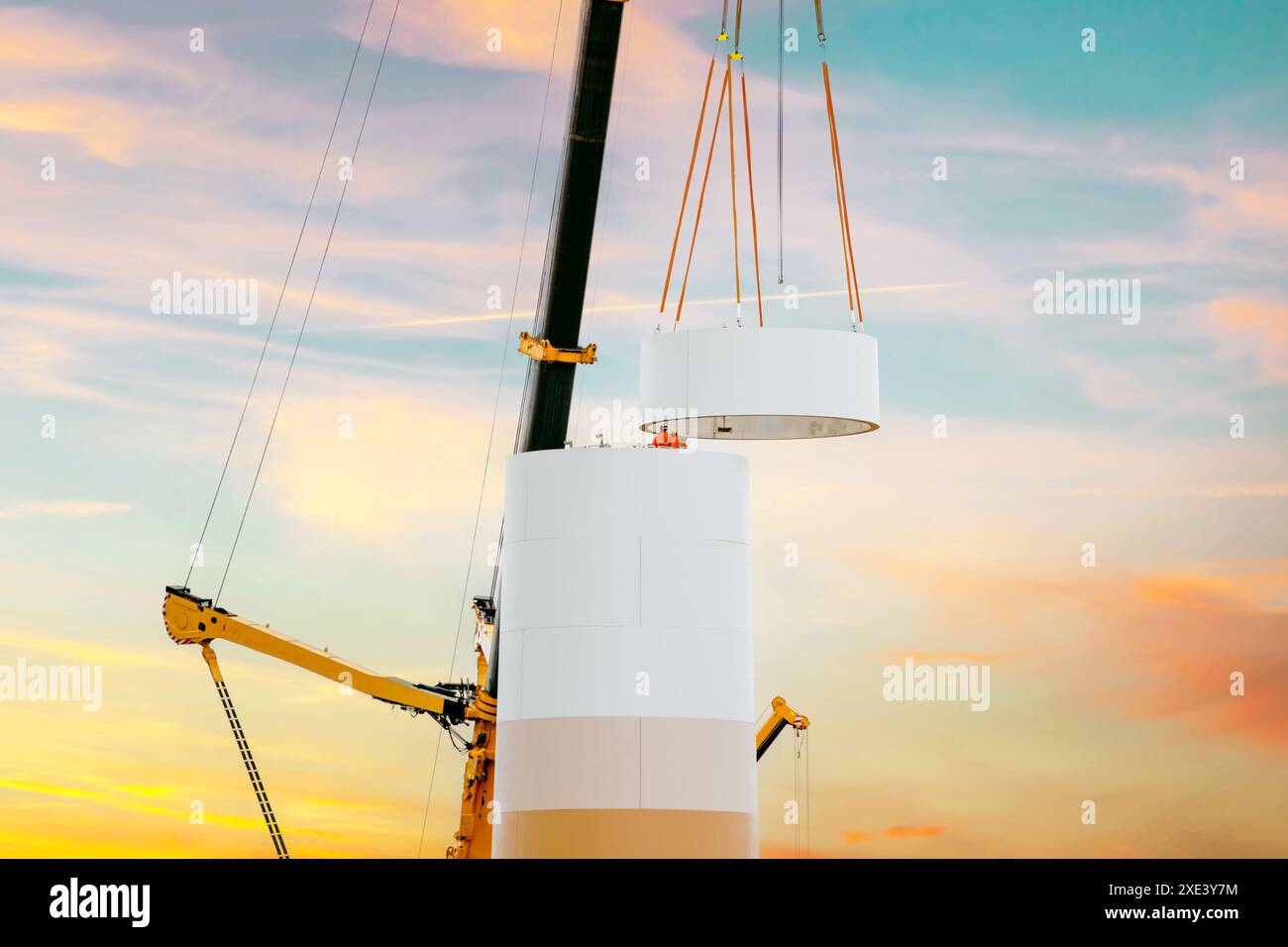 Building and assembling a construction windmill by crane. Farmland with ...