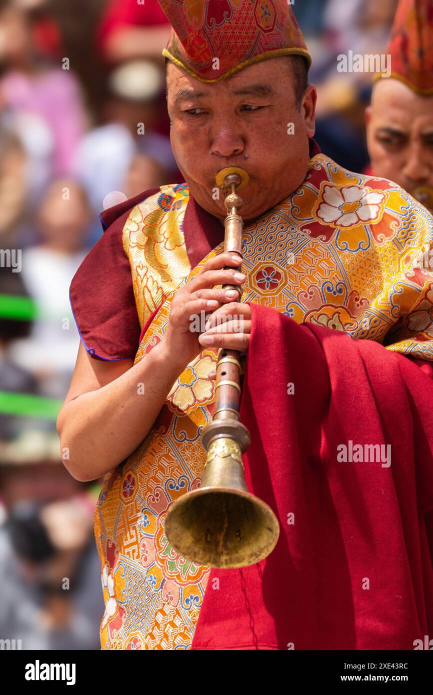A Ladakhi monk playing a musical instrument wearing traditional costume ...