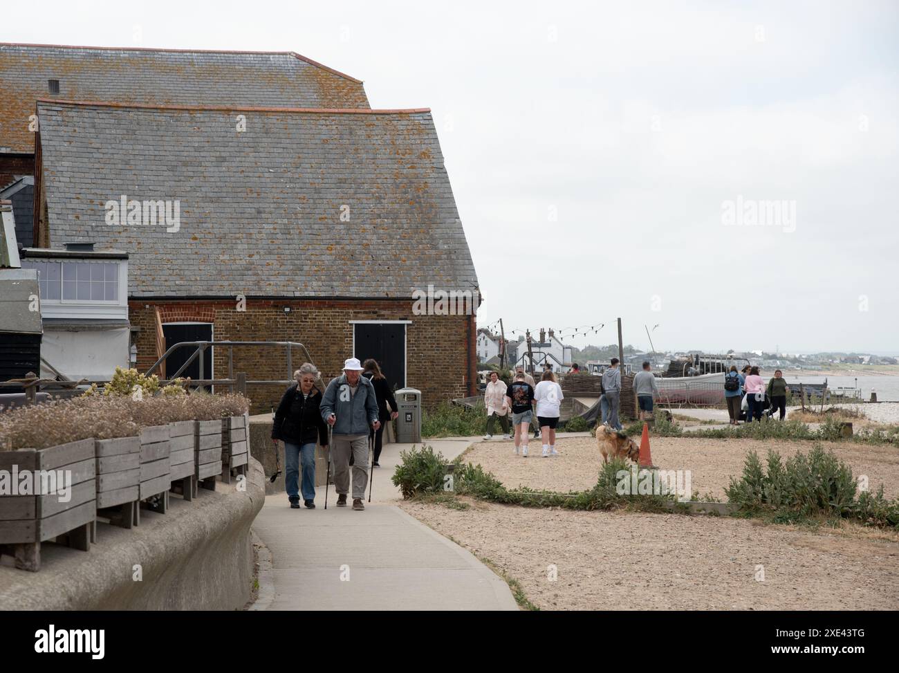 Tourists and locals walk along the seafront pathway seaside with ...