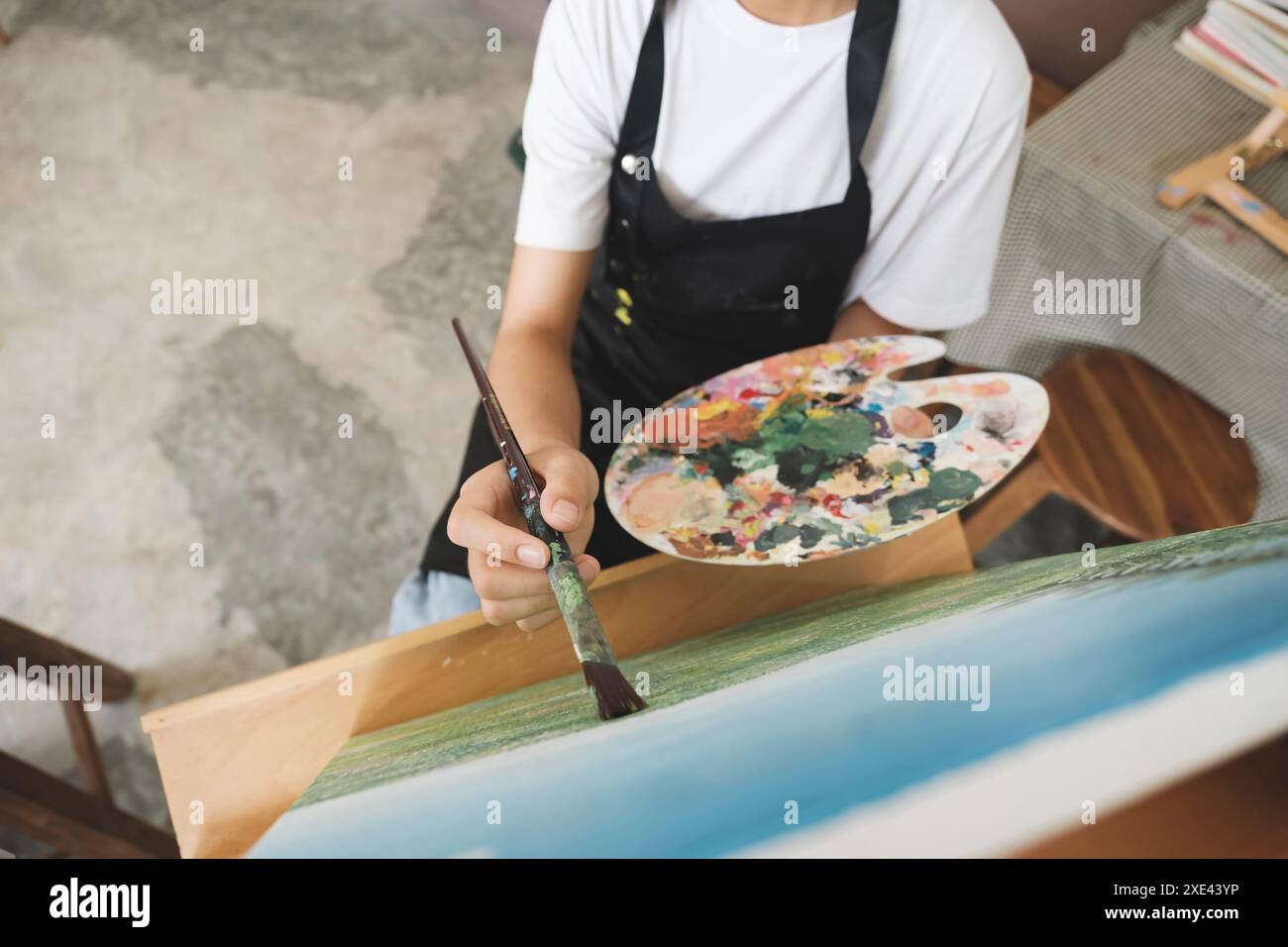 Young Asian female artist painting on canvas doing art projects on her ...