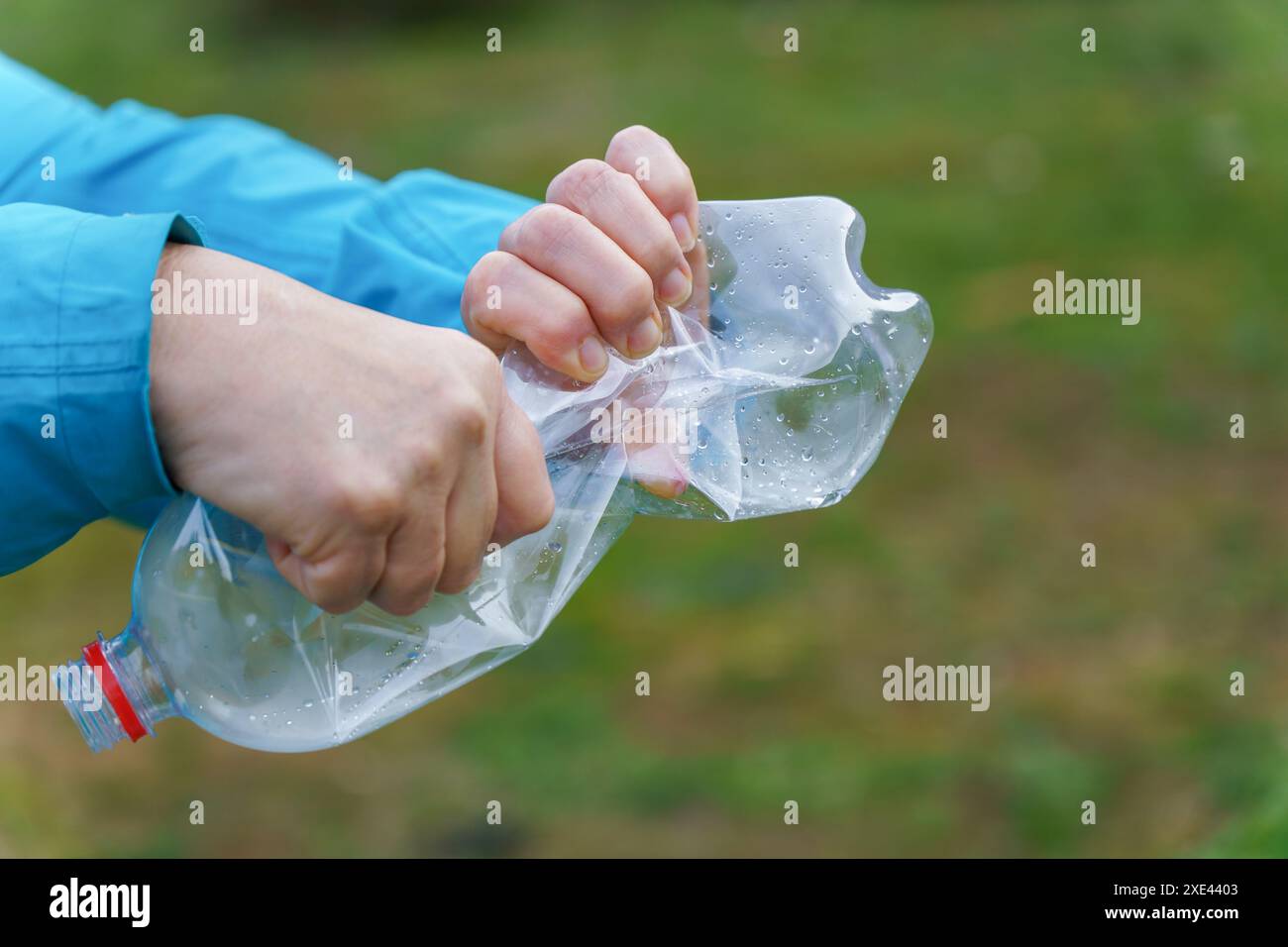 Crush the bottle after use. Close up of woman's hand crushing an empty ...