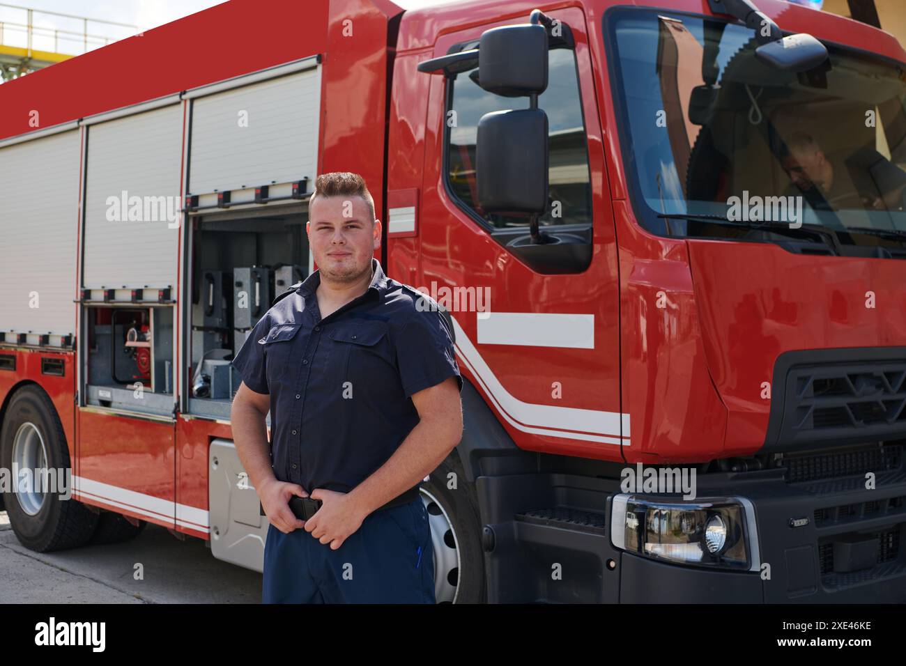 A confident firefighter strikes a pose in front of a modern firetruck ...