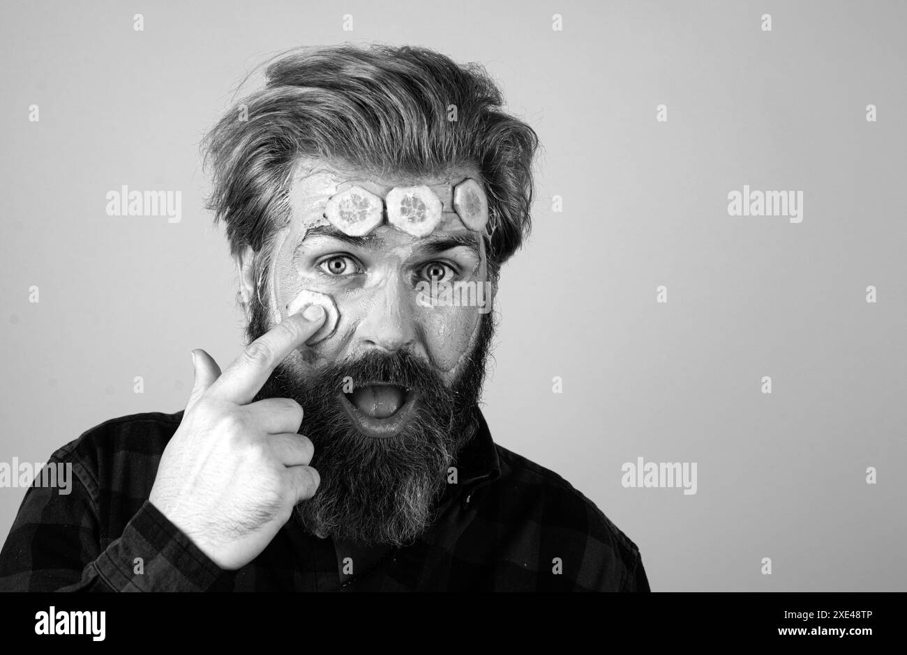 Funny male model with clay mask and cucumber slices on face. Spa ...