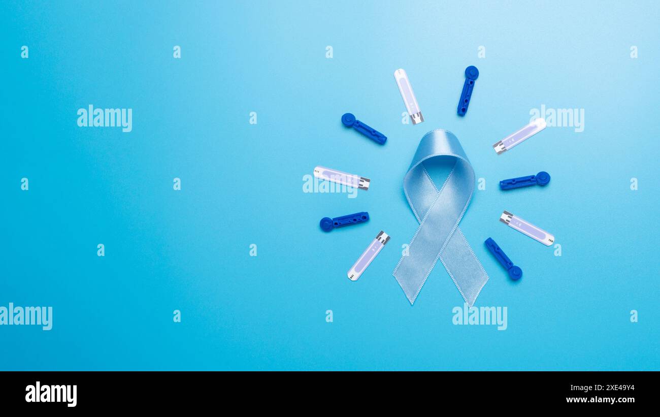 Diabetes awareness concept of ribbon test strips and lancets on blue ...