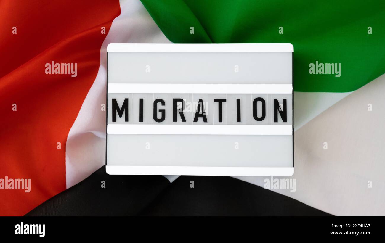 Message MIGRATION on background of UAE flag made from silk. United Arab ...