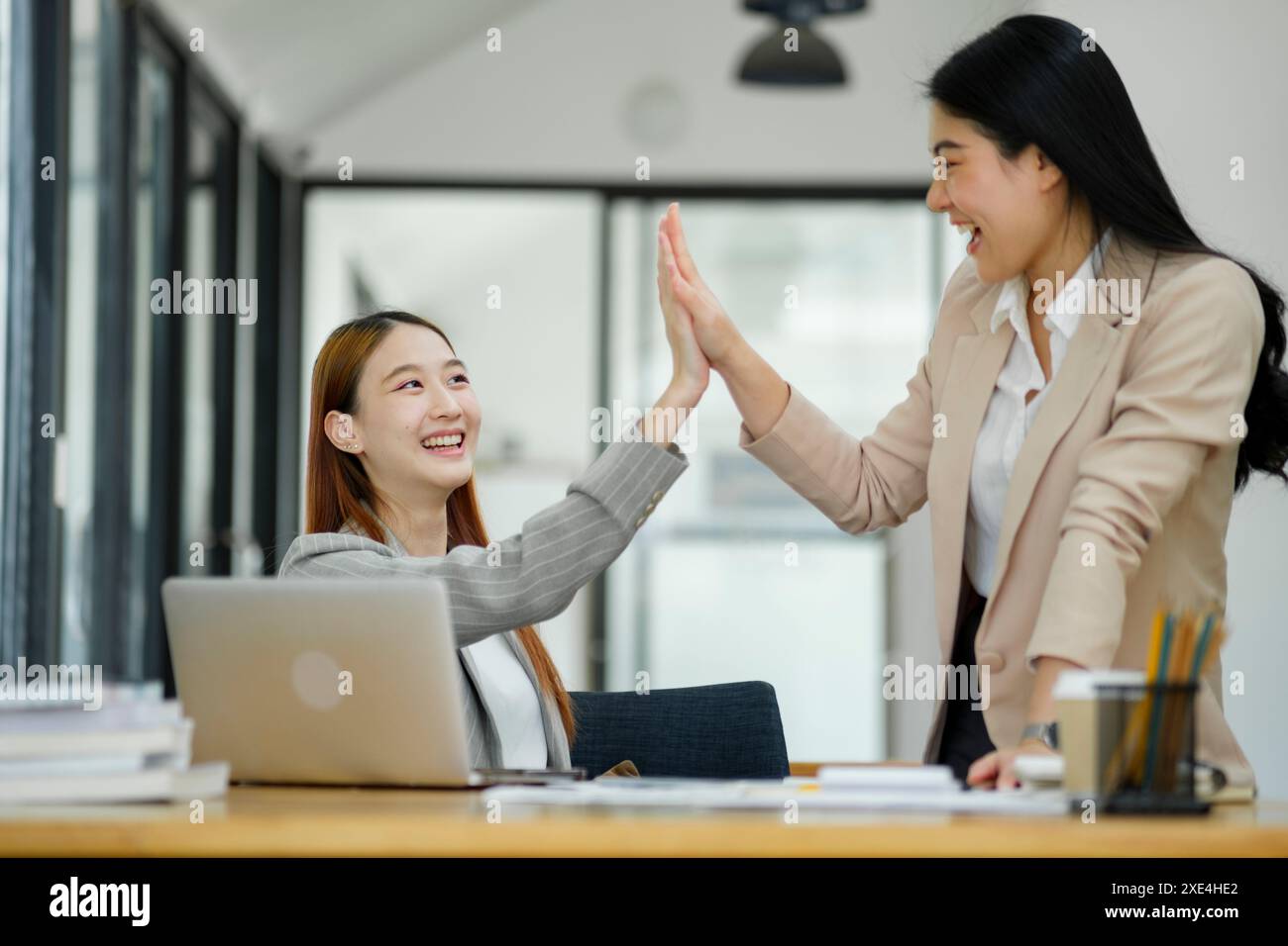 Two women are high-fiving with joy at their success in business. and ...