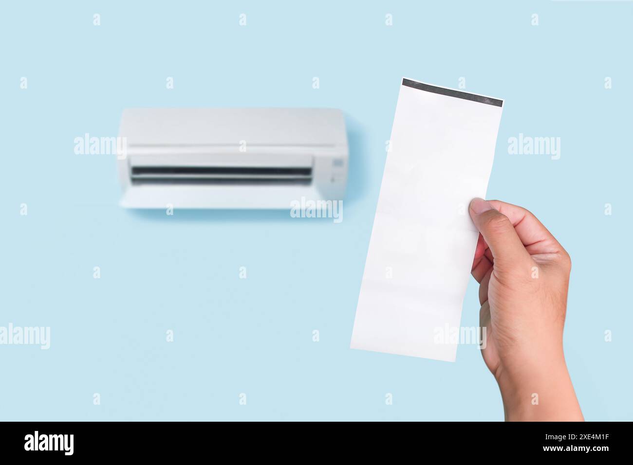 Blank white paper bill holding in a hand with air conditioner blurred ...